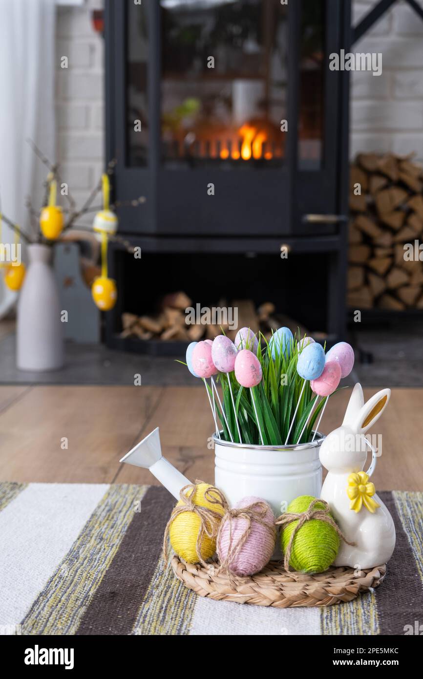 Easter decor near fireplace stove with fire and firewood. Cozy home ...
