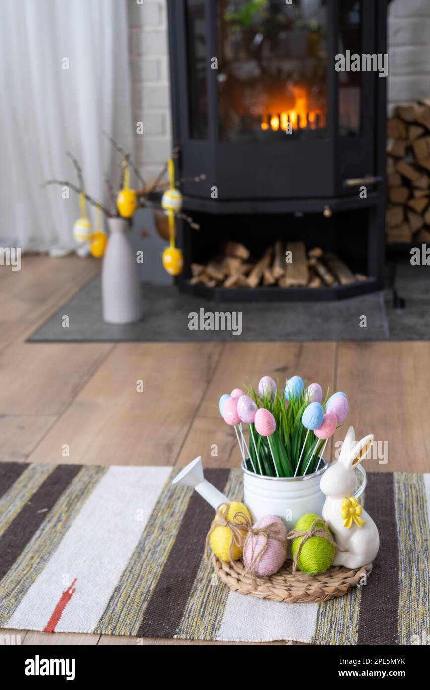 Easter decor near fireplace stove with fire and firewood. Cozy home ...