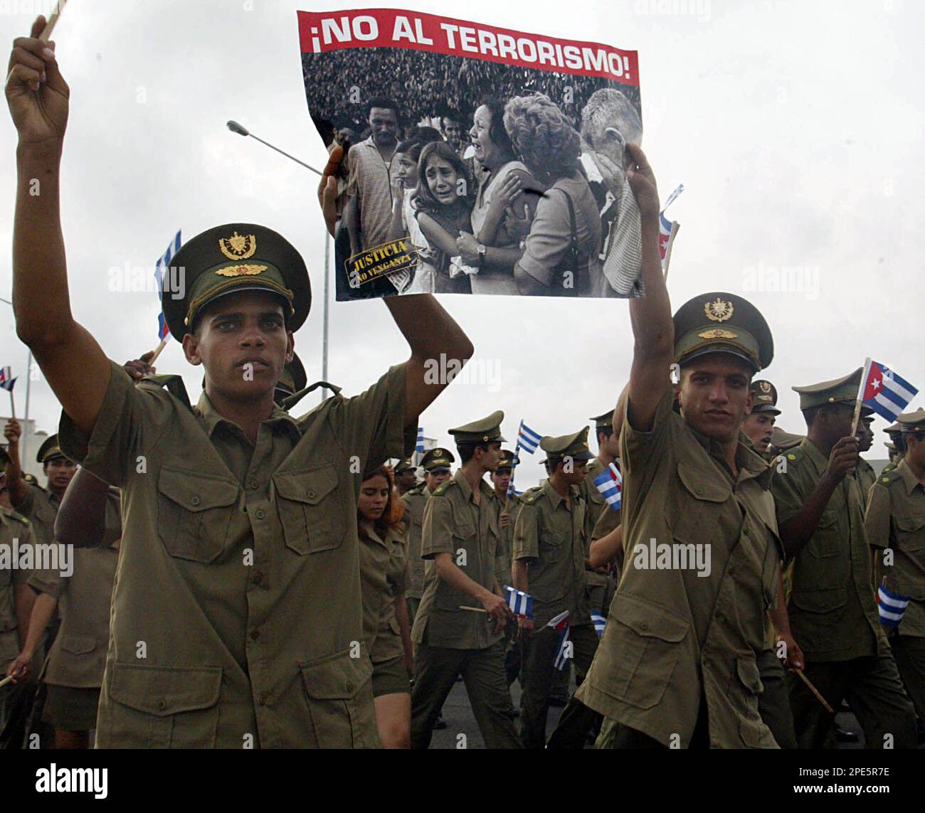 Cuban military officers hold a poster showing relatives of the victims ...