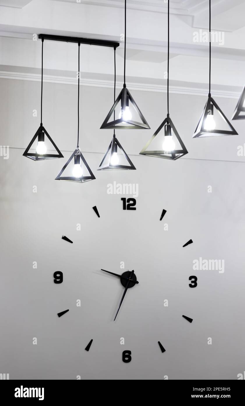 Minimalistic design of a wall clock with black numbers and a light bulb ...