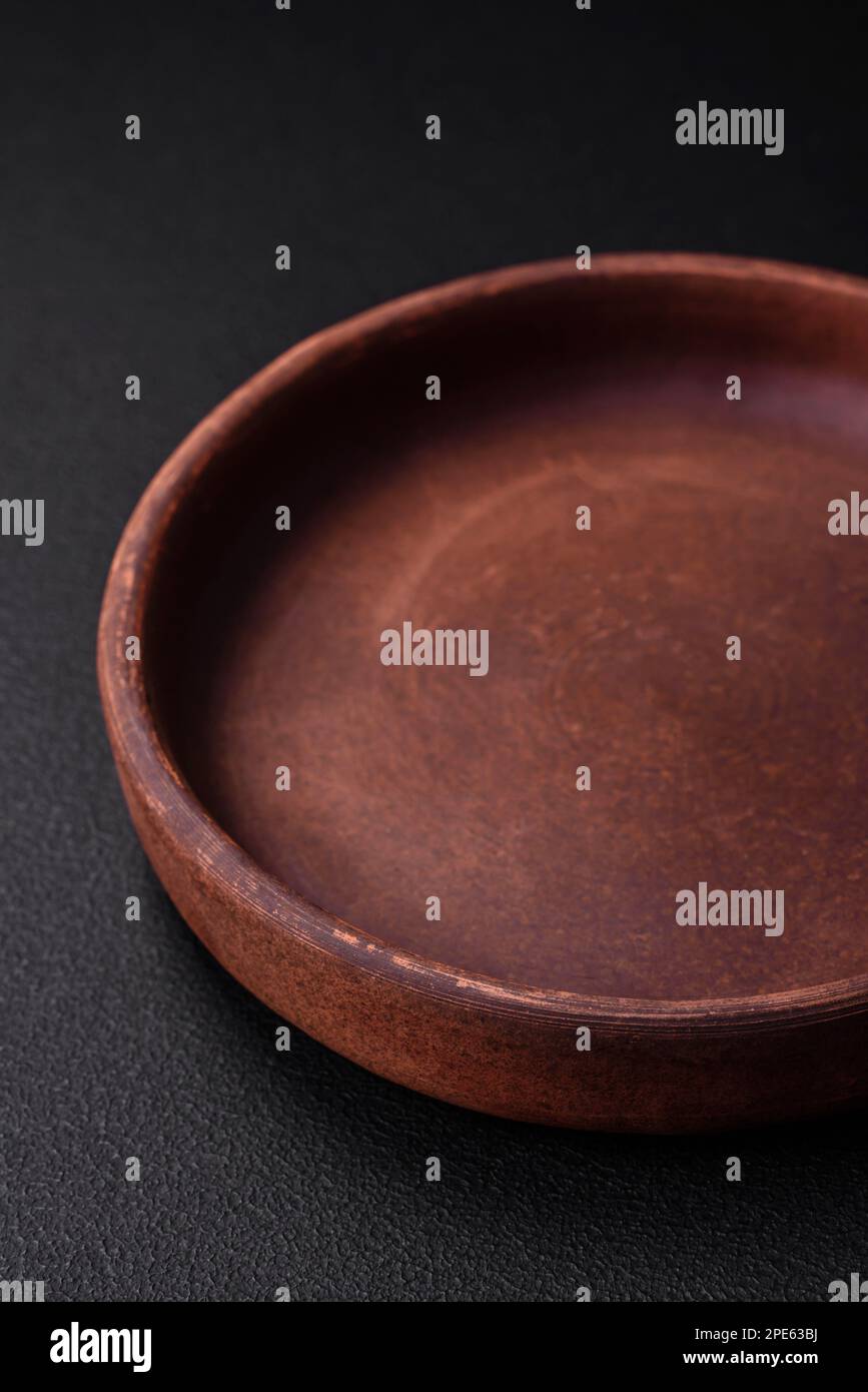 Empty brown colored ceramic plate on dark textured concrete background ...