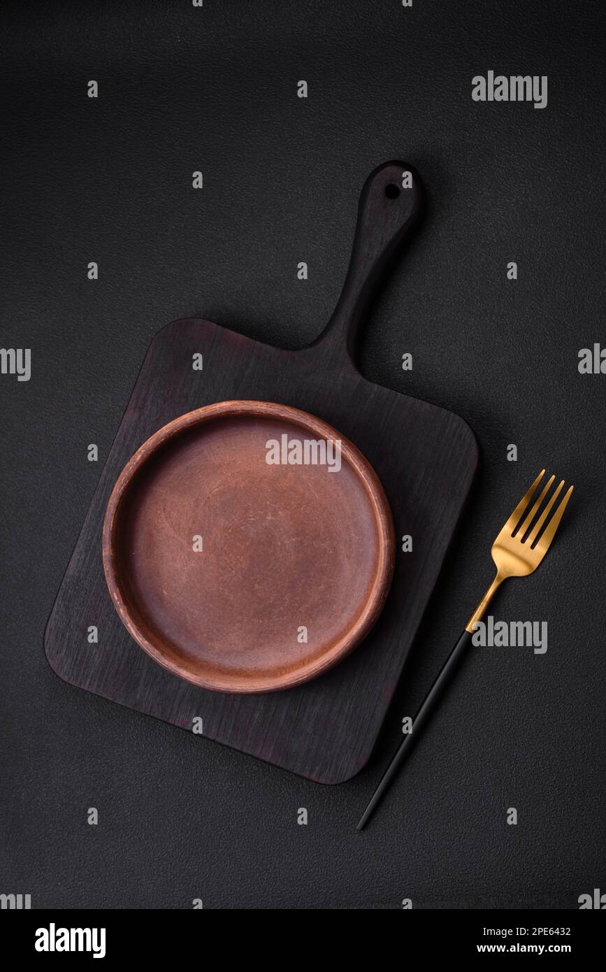 Empty brown colored ceramic plate on dark textured concrete background ...