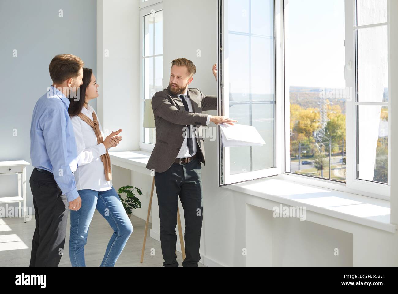 Male realtor shows apartment for sale and its view from window to young ...