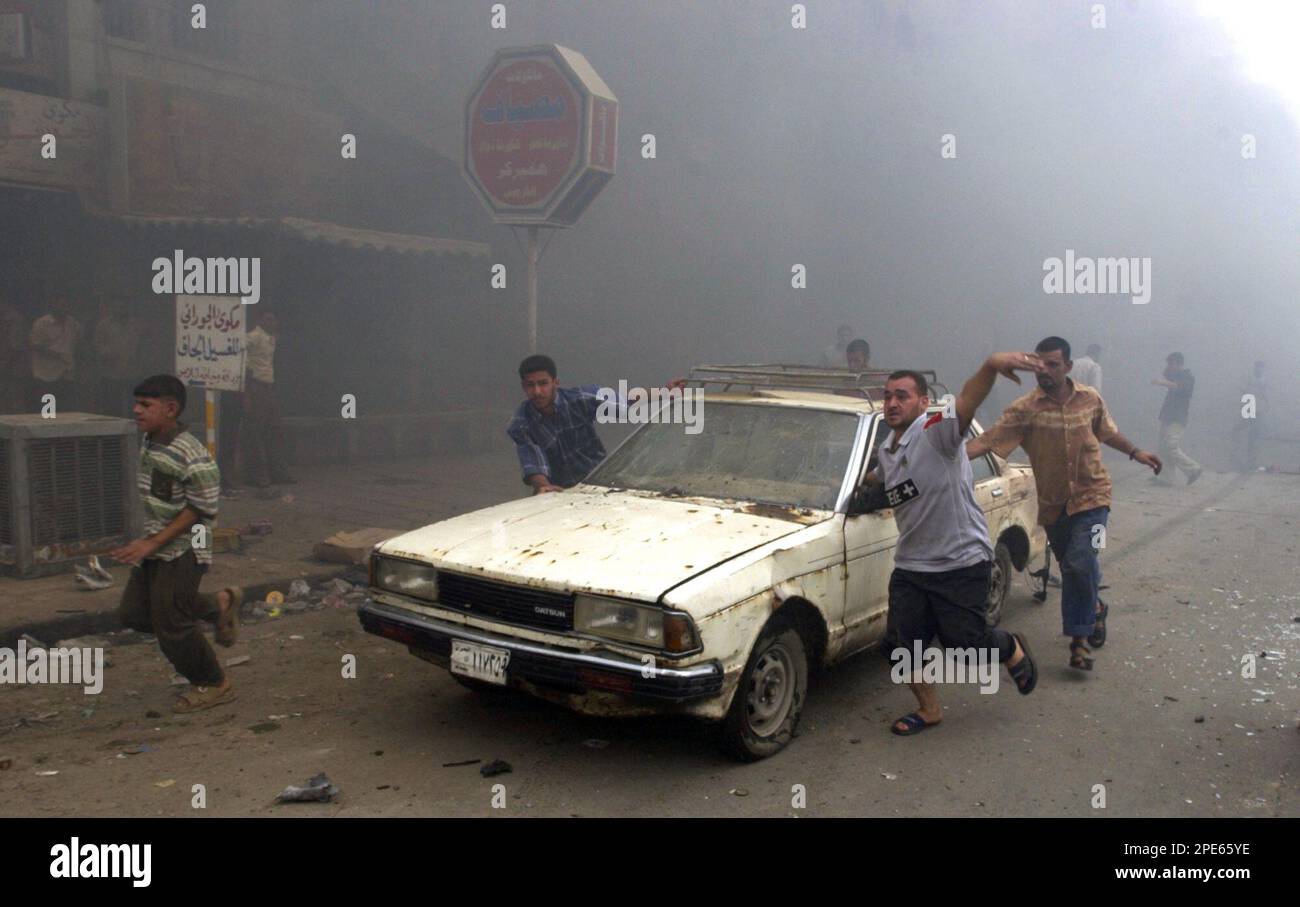 Iraqis flee the scene of a car bomb explosion near a market in eastern ...