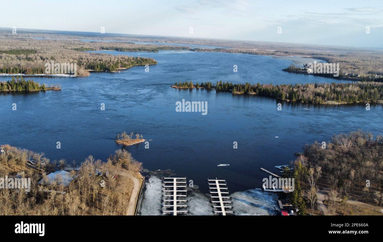 A large dam surrounded by a vast body of water and lush, green trees ...