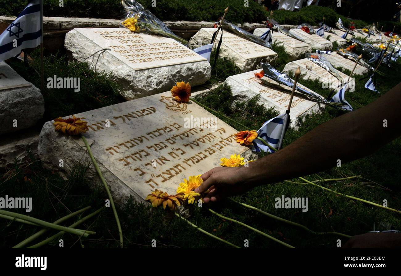 A Israeli soldier lays a flower on a comrade's grave after a ceremony ...
