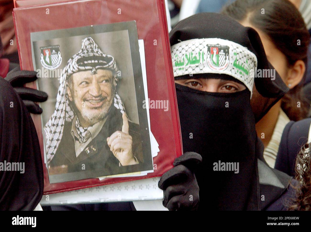A veiled Palestinian student holds her diploma with a picture of Yasser ...