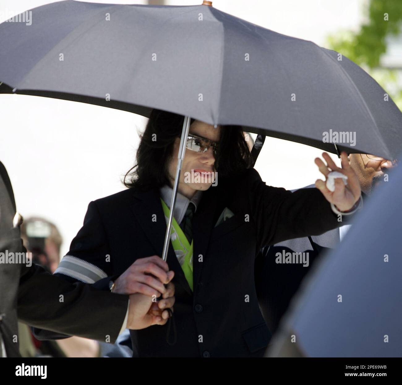 Holding his umbrella with help from a security guard, Michael Jackson ...