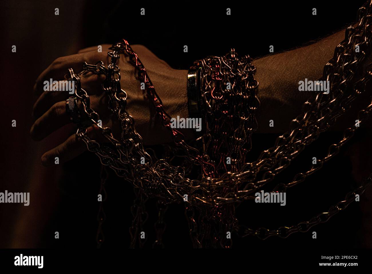 Male hand holding chains on a dark background Stock Photo - Alamy