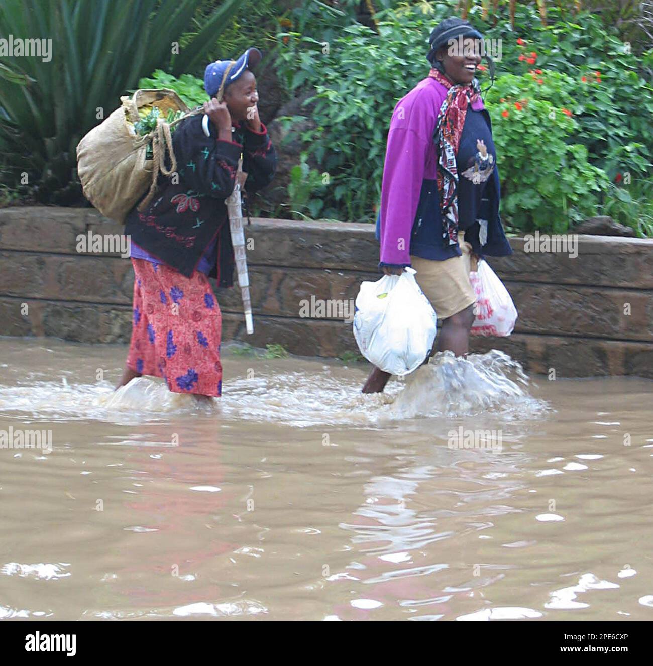 Kenyans pass through a flooded road in Nairobi, Monday, May 9, 2005 ...