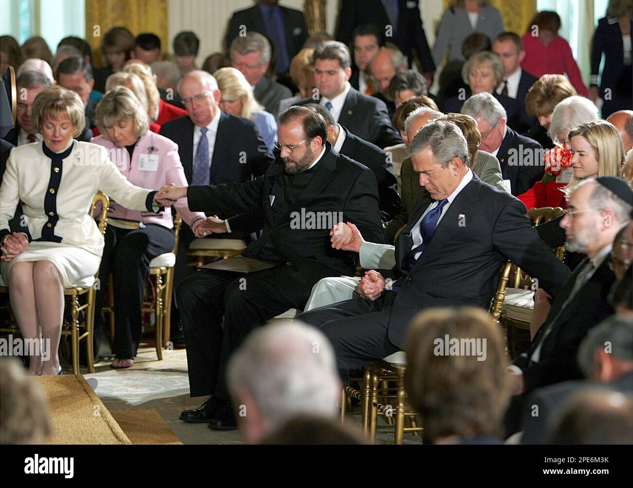 President Bush holds hands and prays with guests during the National ...