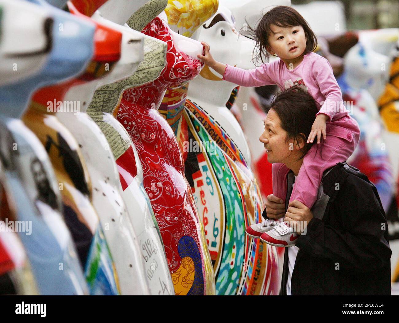 A girl getting a piggyback ride on her father touches the nose of one ...
