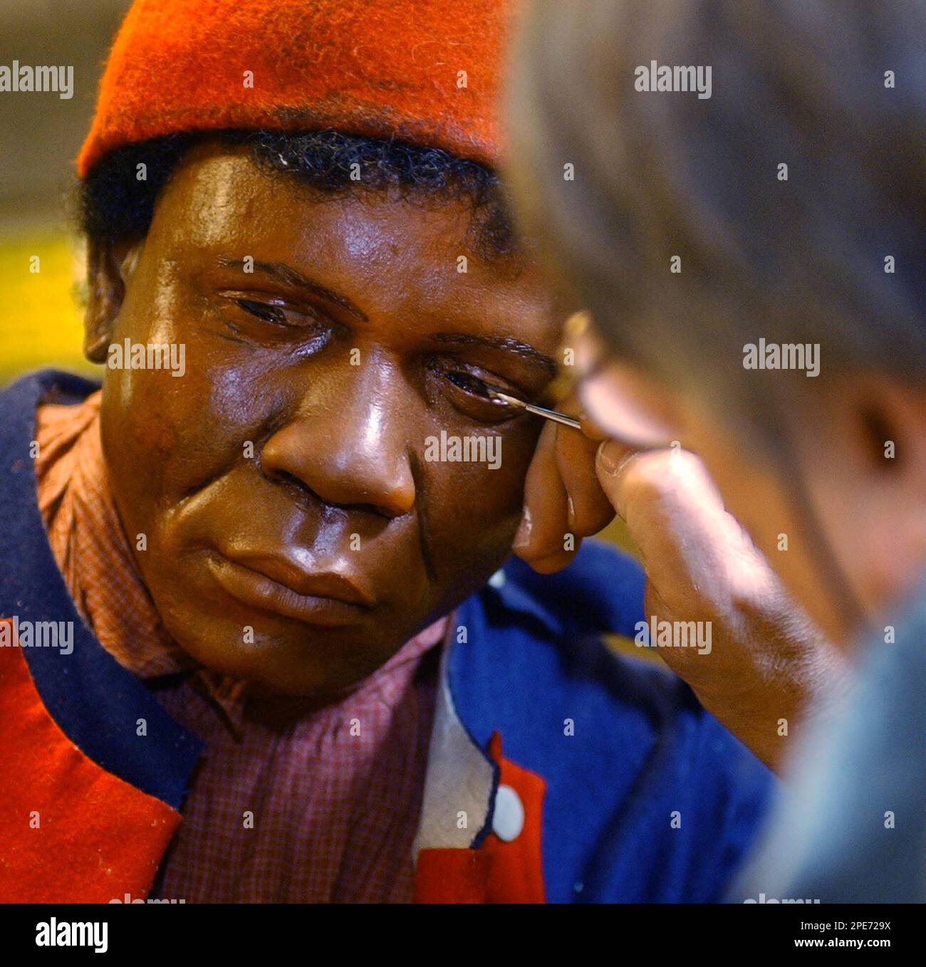 Model maker Gerry Embleton paints the eyes of a figure representing ...