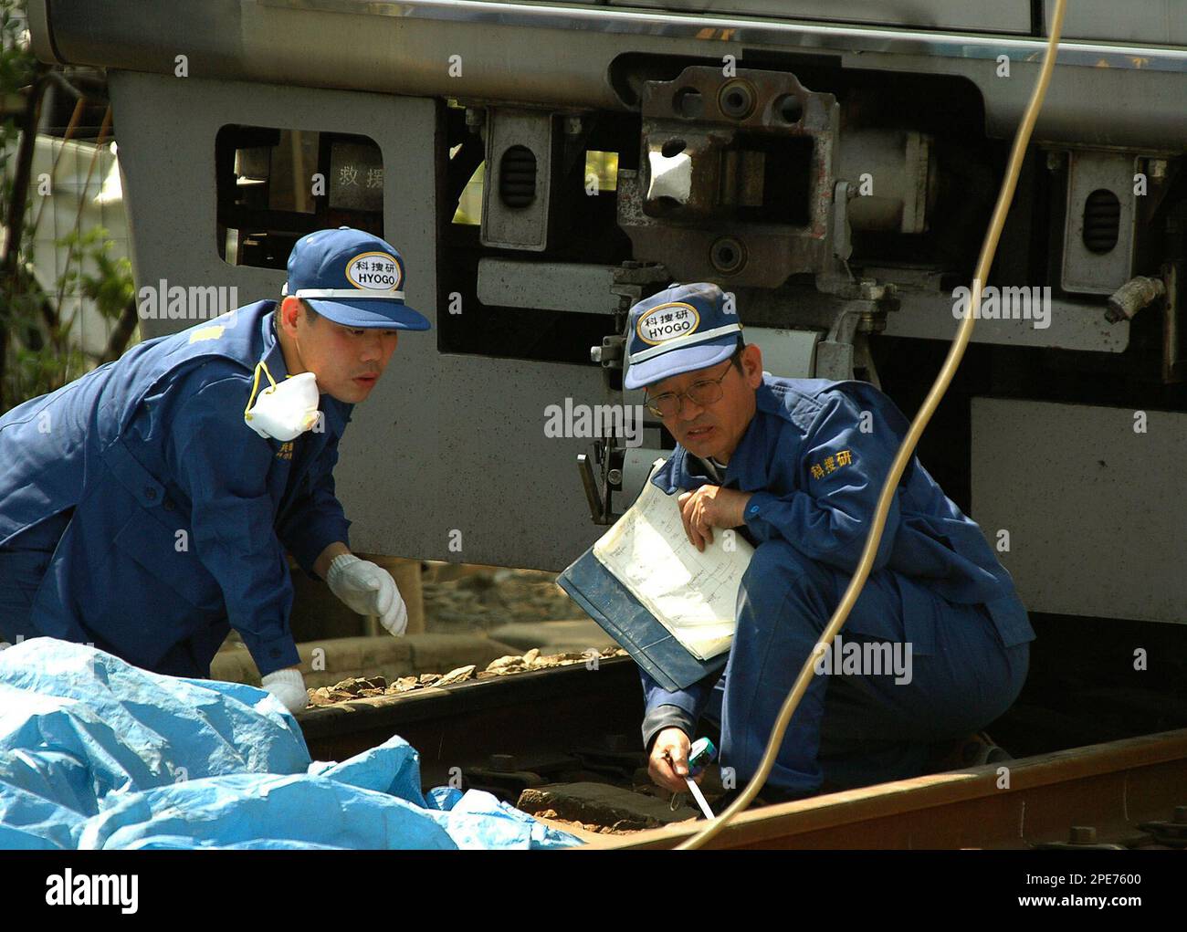 Police investigators examine the tracks near a derailed train in Amagasaki, western Japan ...