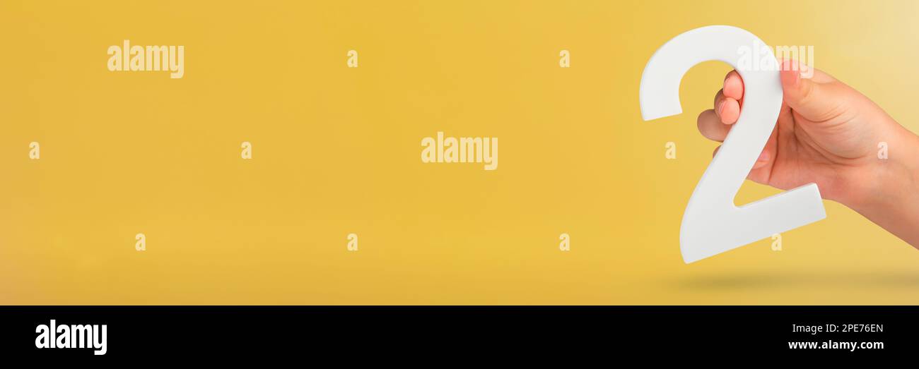 Number two in hand. Hand holding white number 2 on yellow background ...