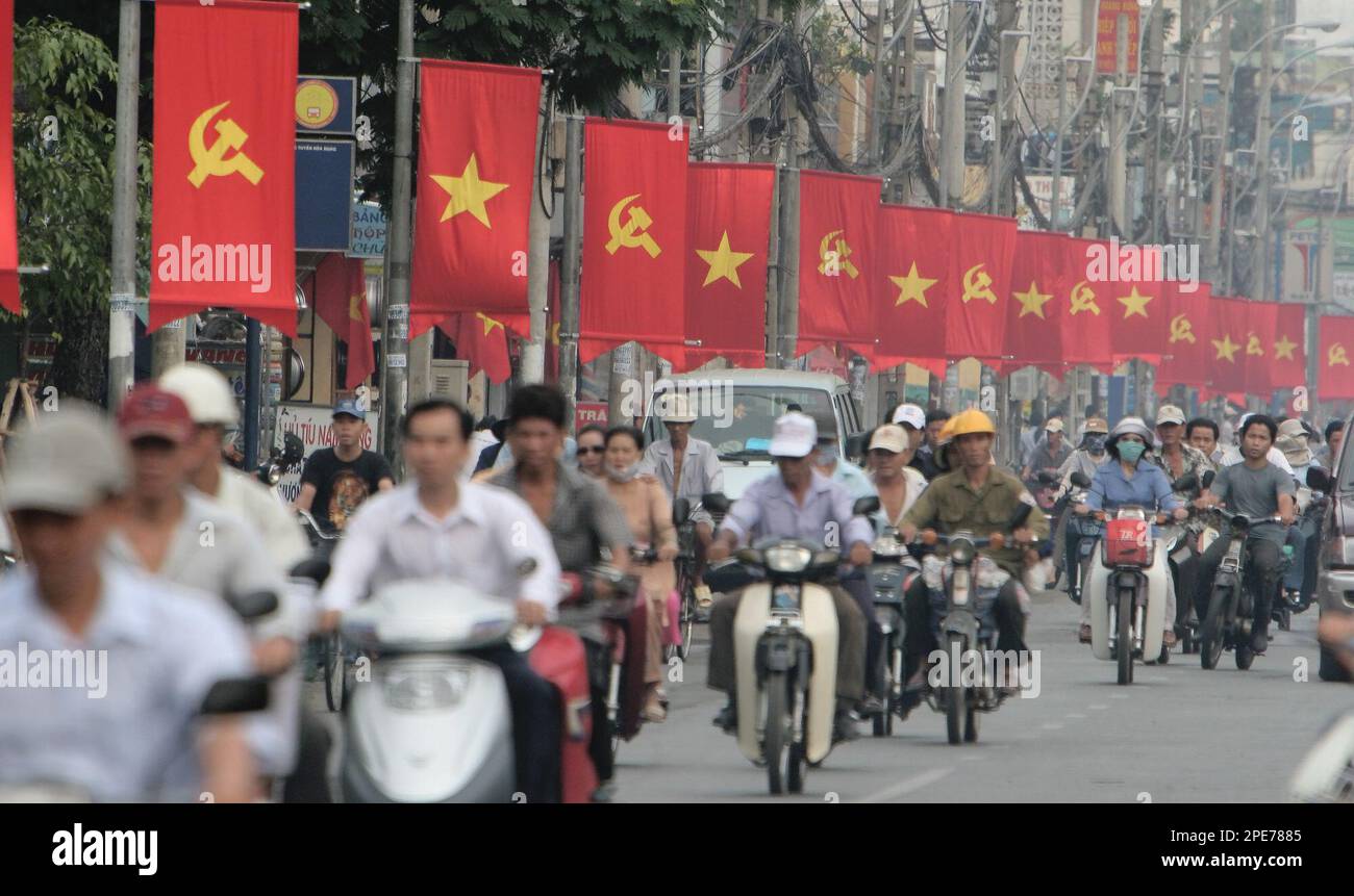 Vietnamese commuters make their way along a road lined with communist ...