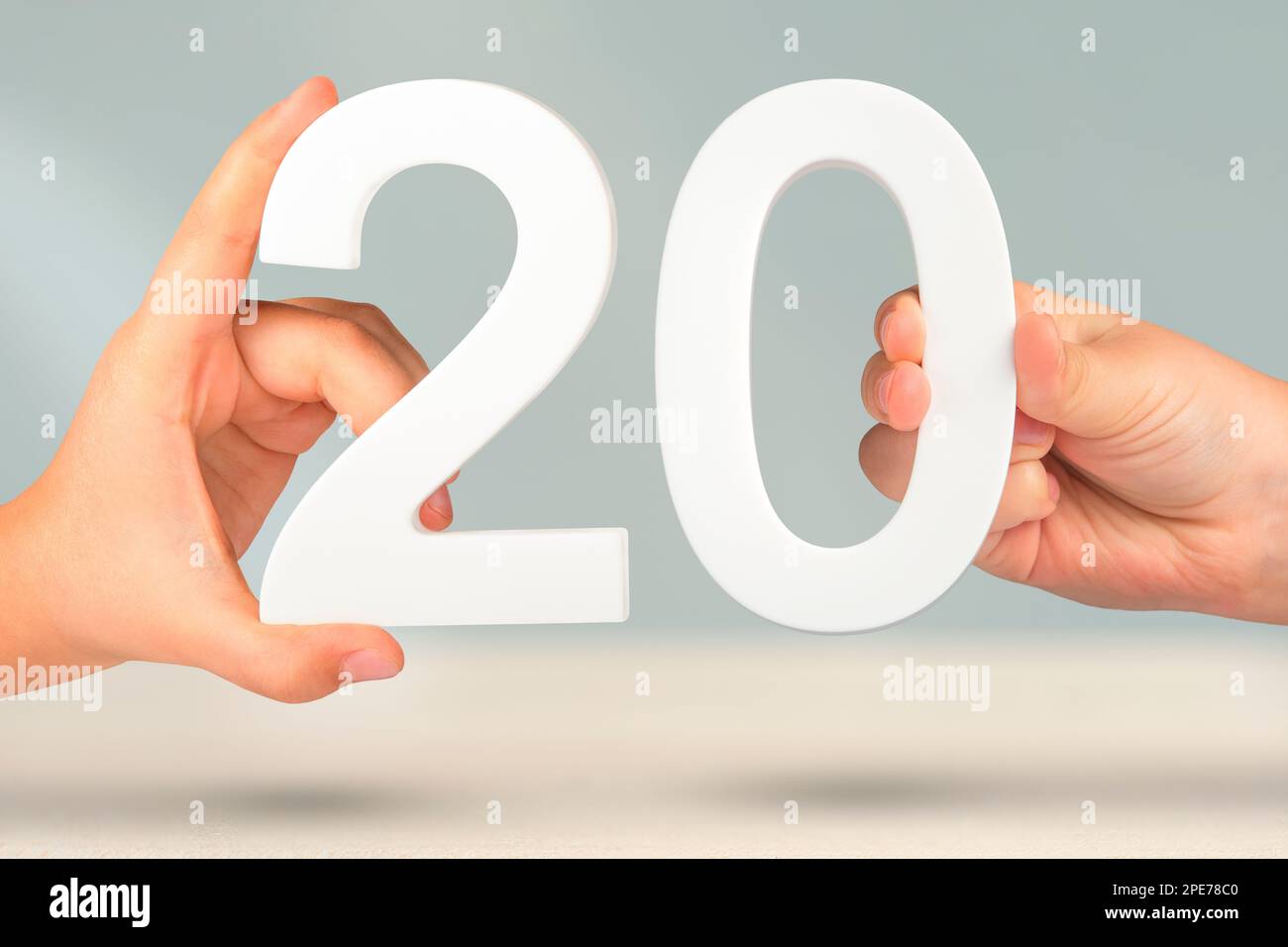 Number twenty in hand. Hand holding white number 20 on blurred ...