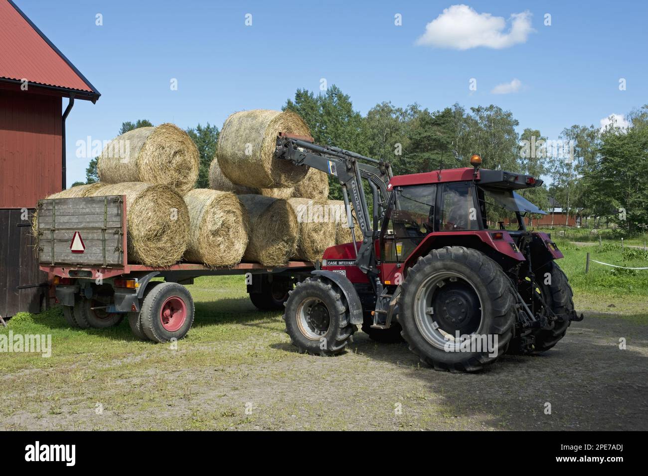 Loading round bale of hay into hayloft with front loader bale spike on ...