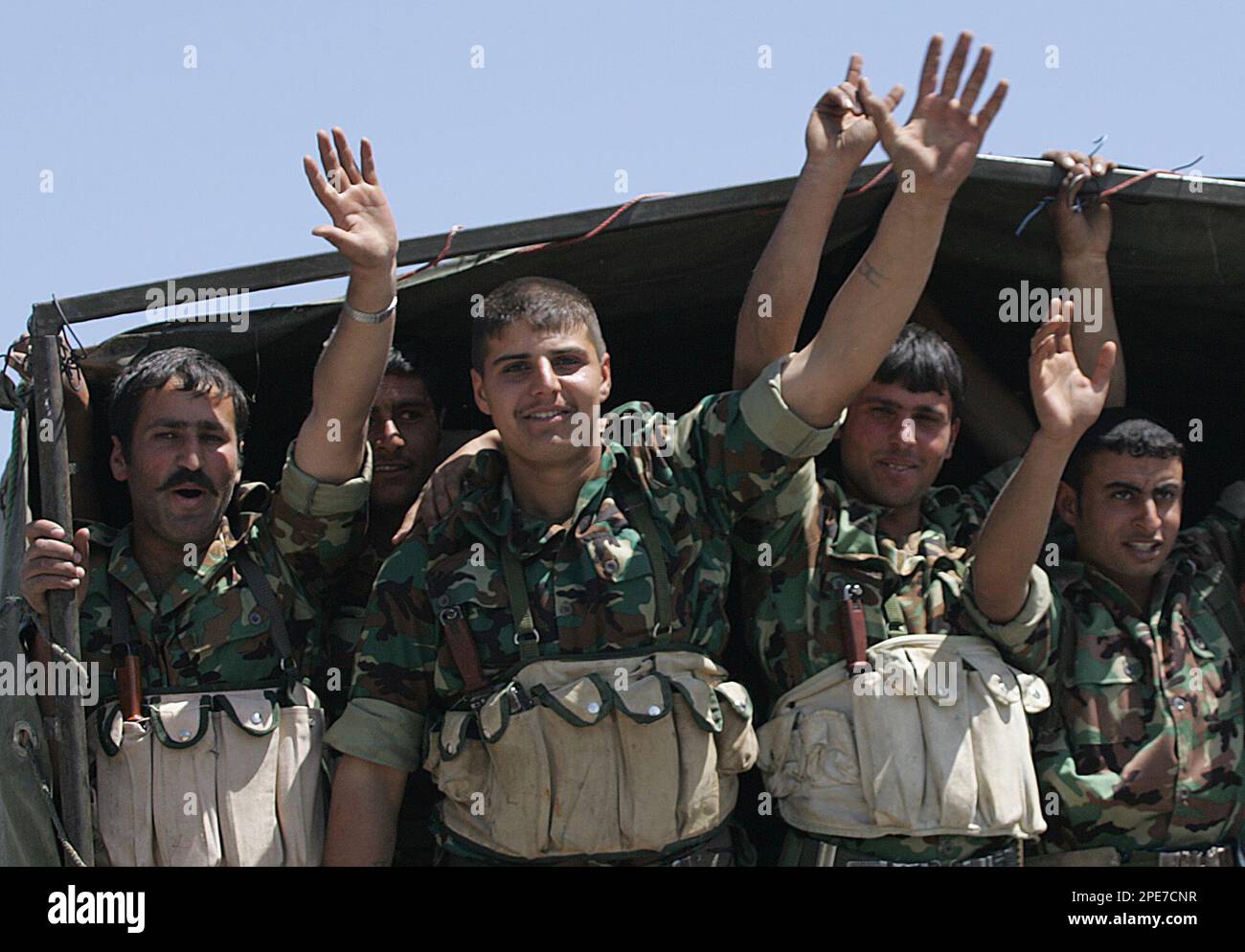 Syrian soldiers standing in their army truck wave goodbye as they cross ...