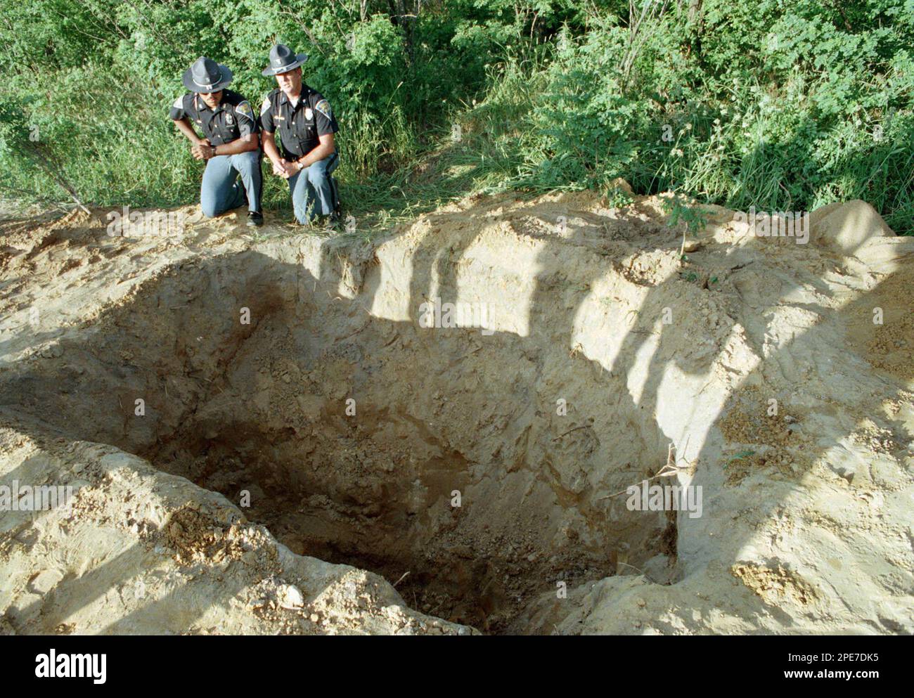 **FILE**Two Indiana state troopers kneel at the edge of a grave where ...
