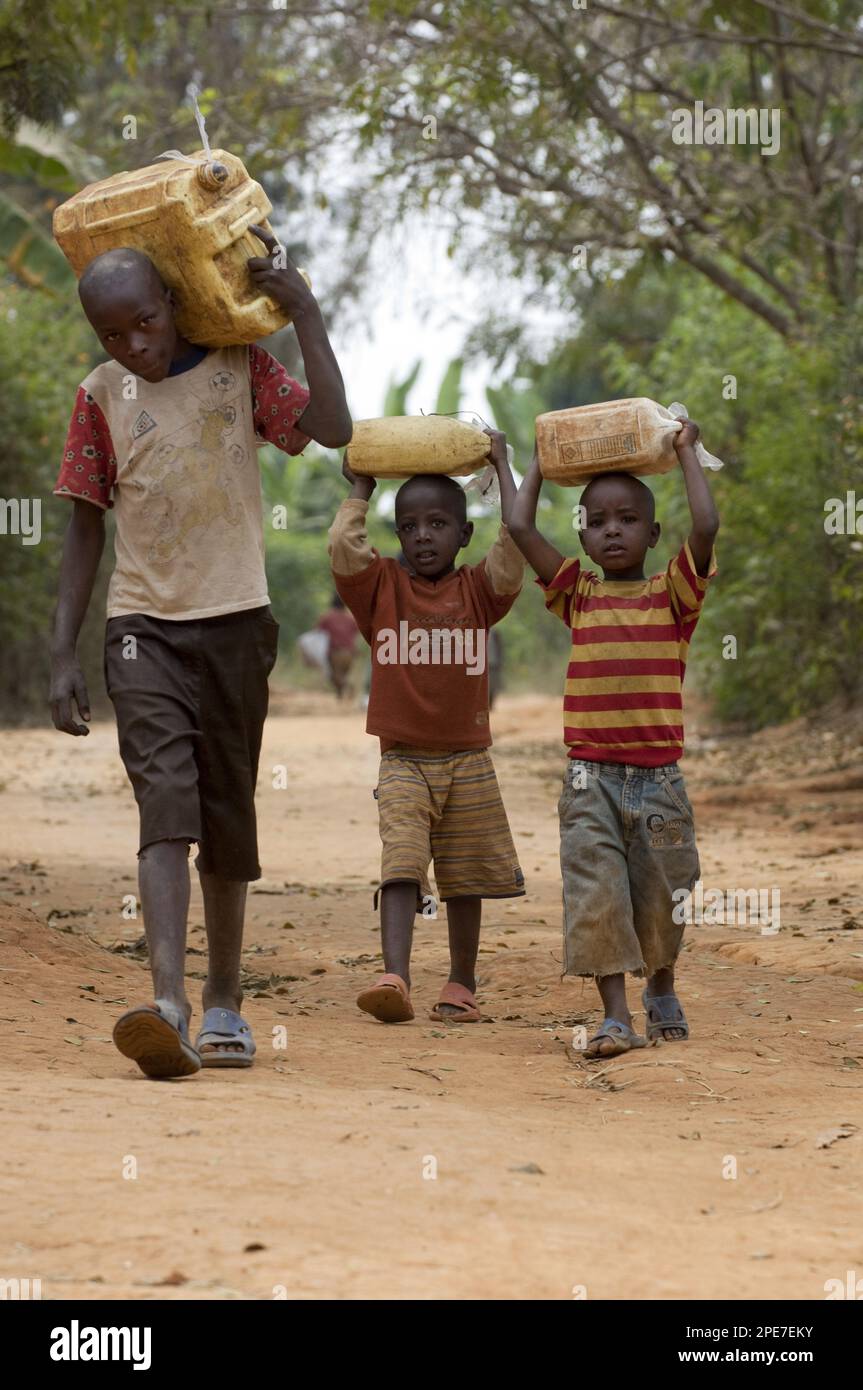 Children collecting water from a well and carrying it home, Rwanda ...