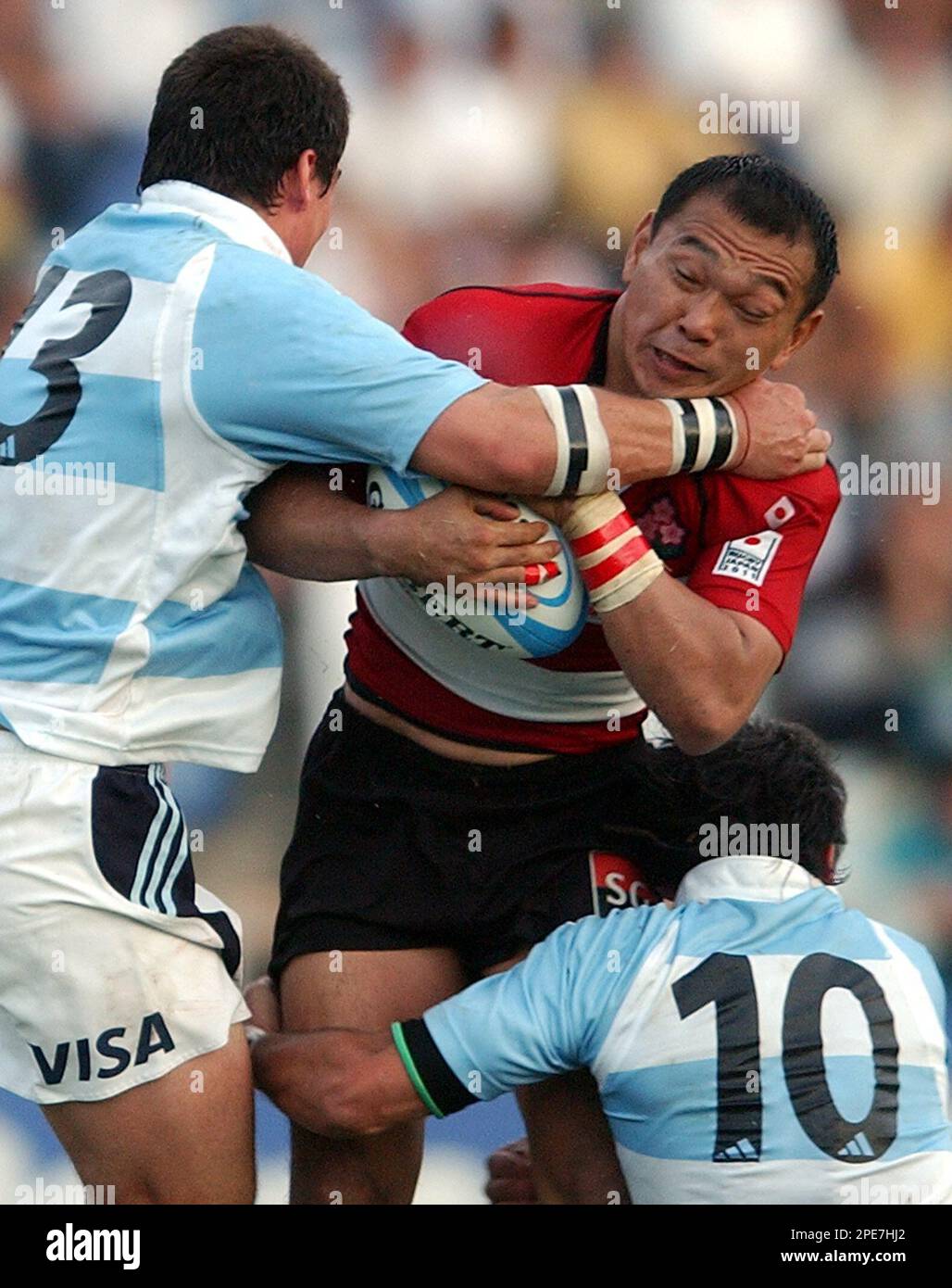 Yukio Motoki, center, of Japan's national rugby team, is tackled by ...