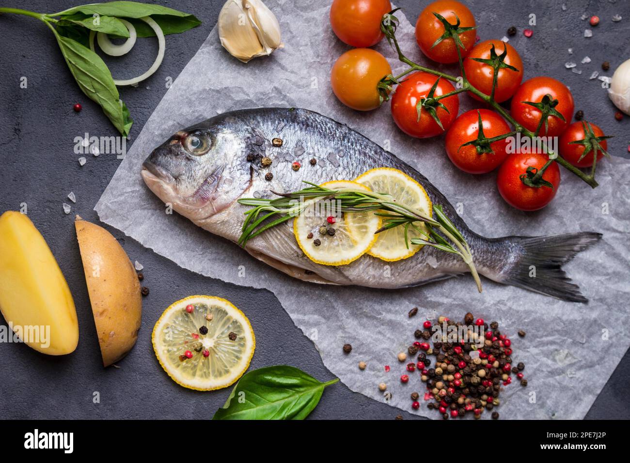 Raw whole fish with fresh ingredients ready to cook. Sea bream, lemon ...