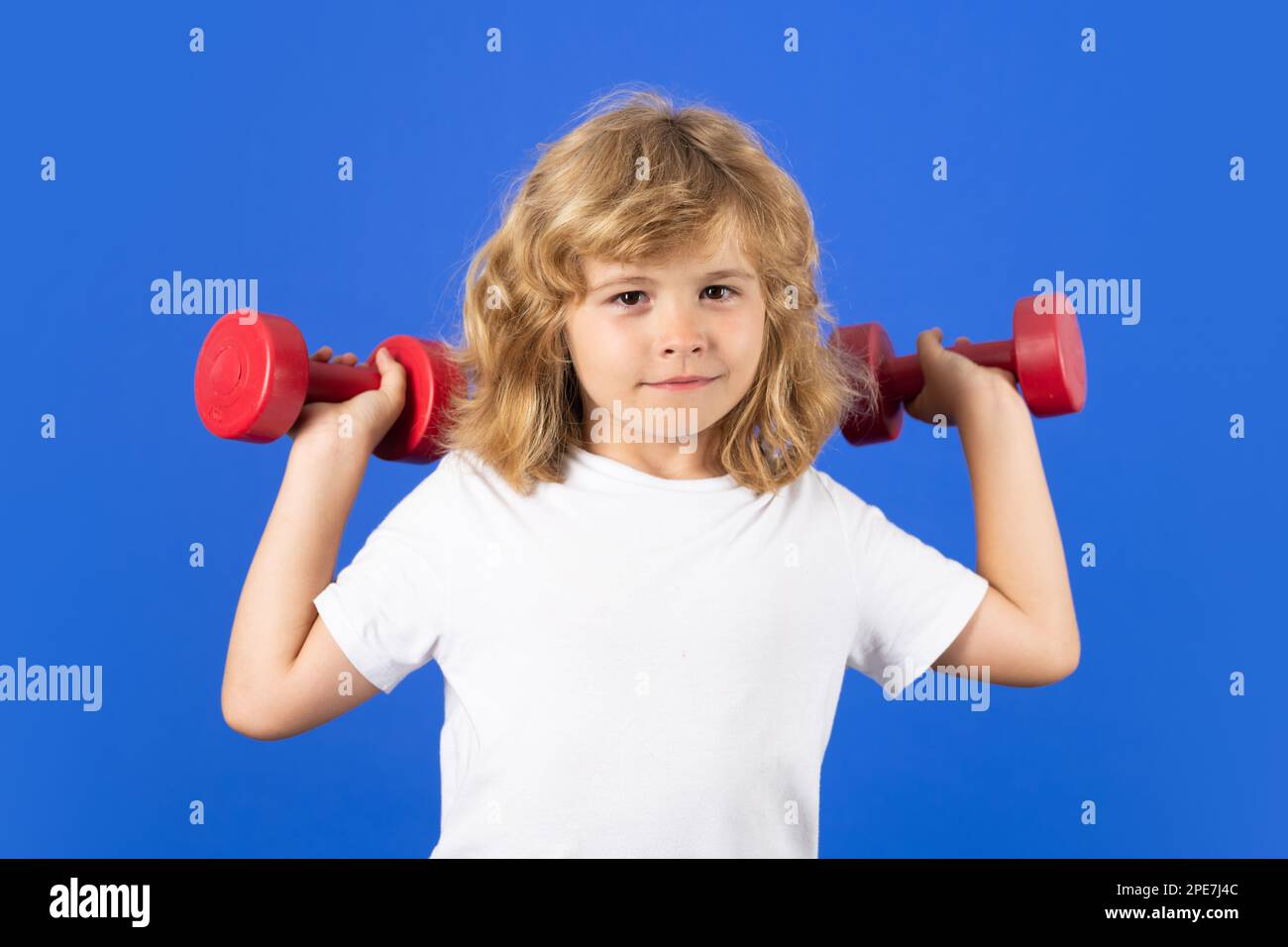 Child boy pumping up biceps muscles with dumbbell. Fitness kids with ...
