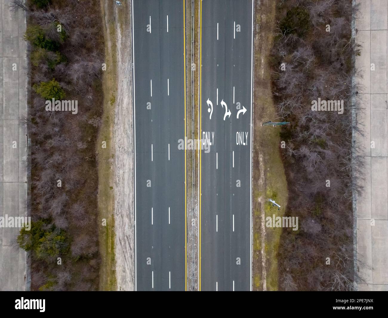 An aerial top view of symmetrical empty roads with grass and trees on ...