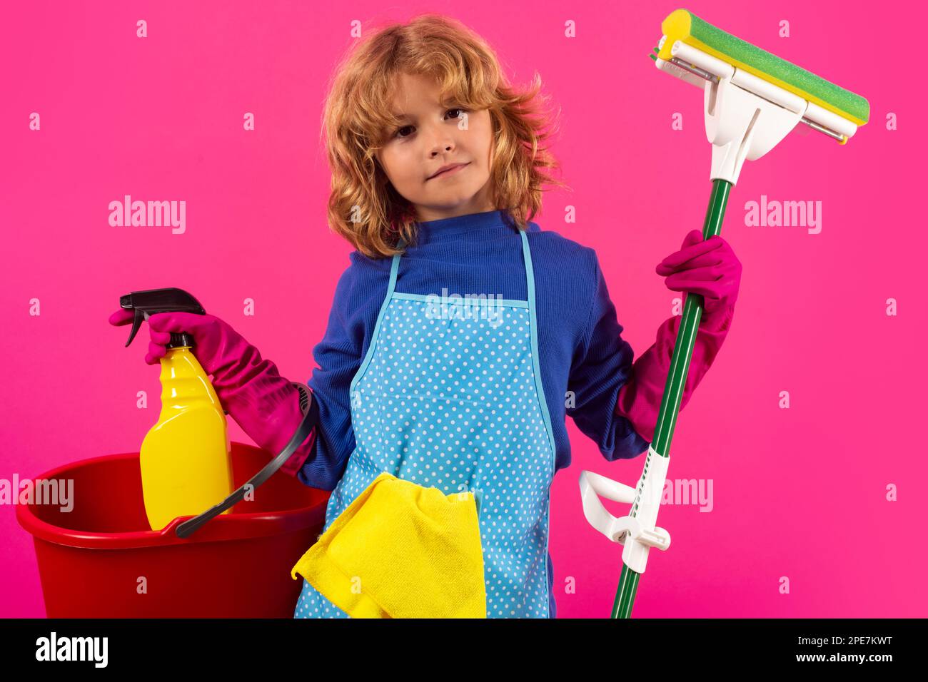 Child doing housework. Studio portrait of child use duster and gloves ...