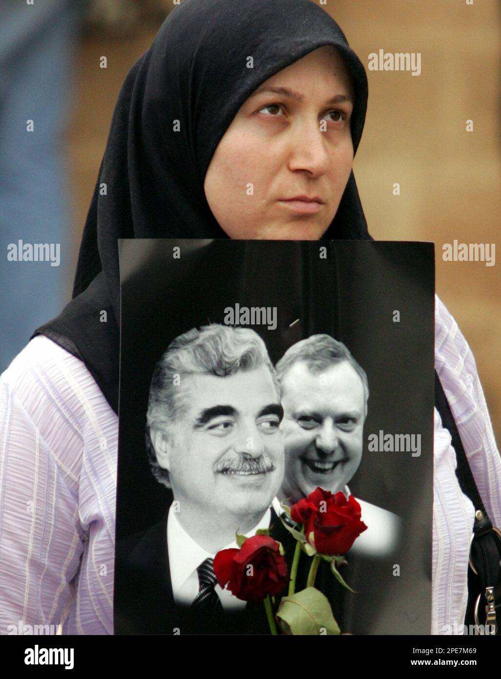 A Lebanese woman holds roses and a poster with the pictures of slain ...
