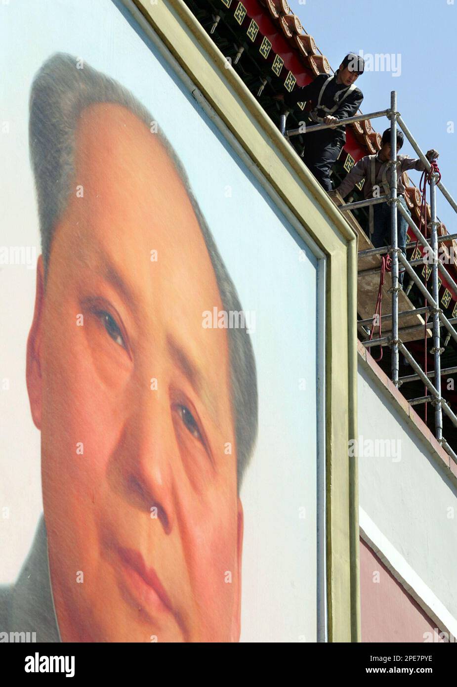Two workers stand on scaffolding above the portrait of late Chinese ...