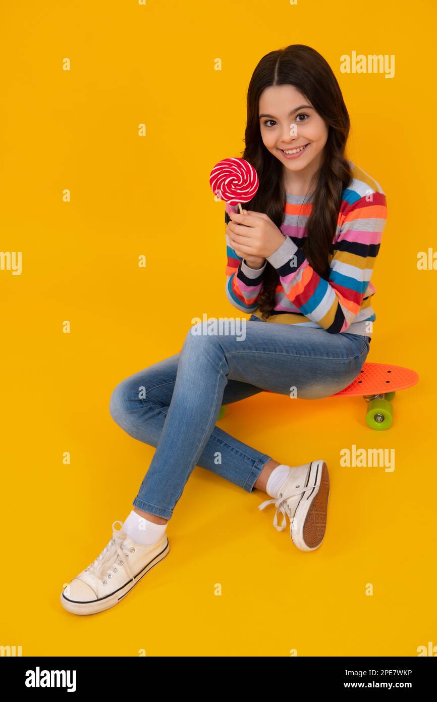 Cool teen child with lollipop over yellow isolated background. Sweet ...