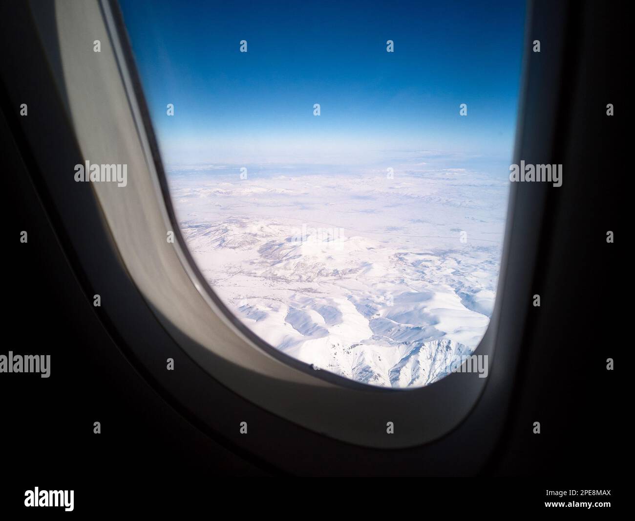 View of snowy landscape through plane porthole Stock Photo - Alamy