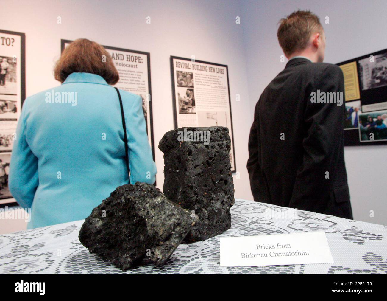 Visitors look at wall displays behind pieces of the brick from the Nazi ...