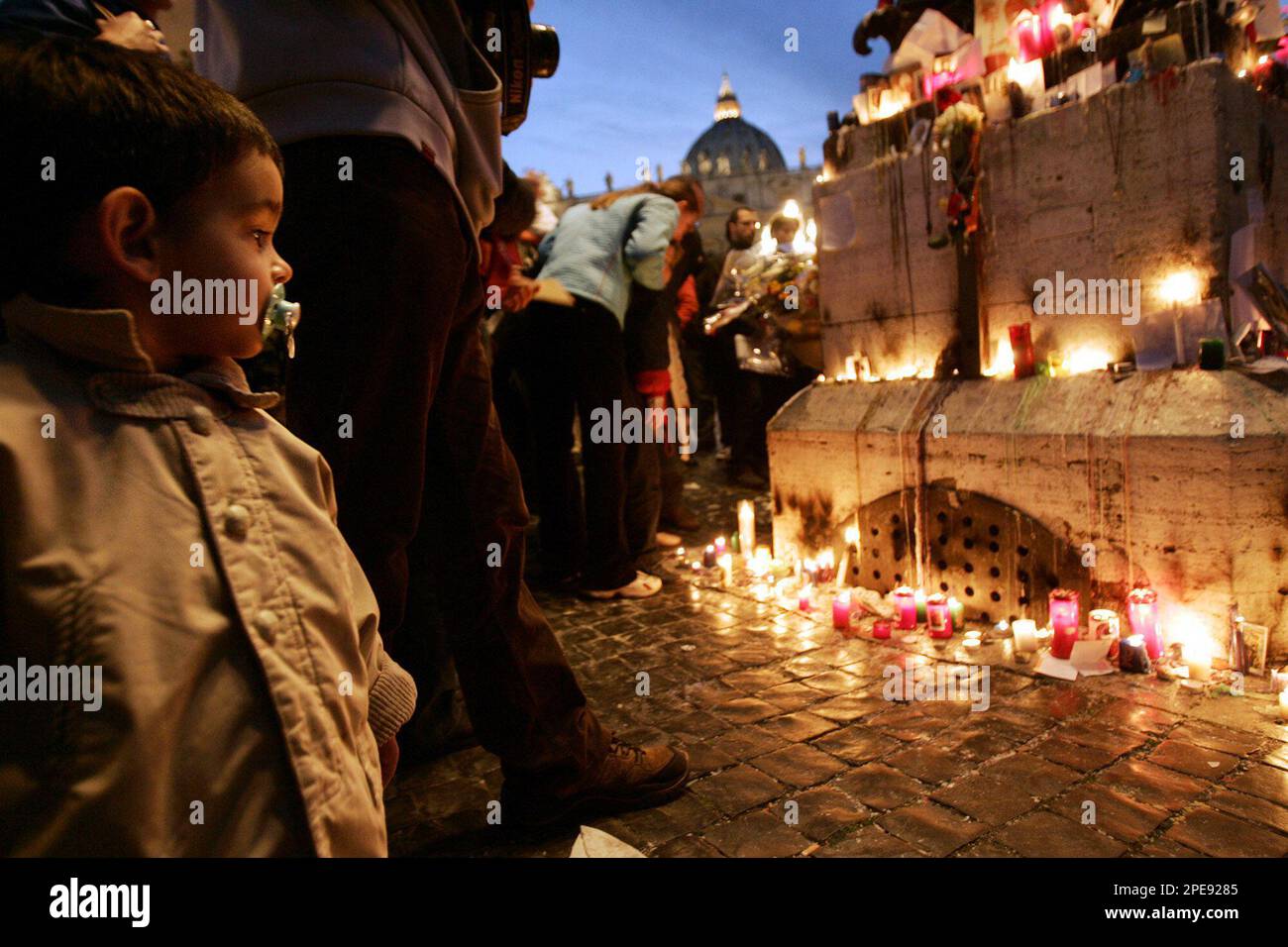 A child with a pacifier looks at candles lit in St. Peter's Square at ...