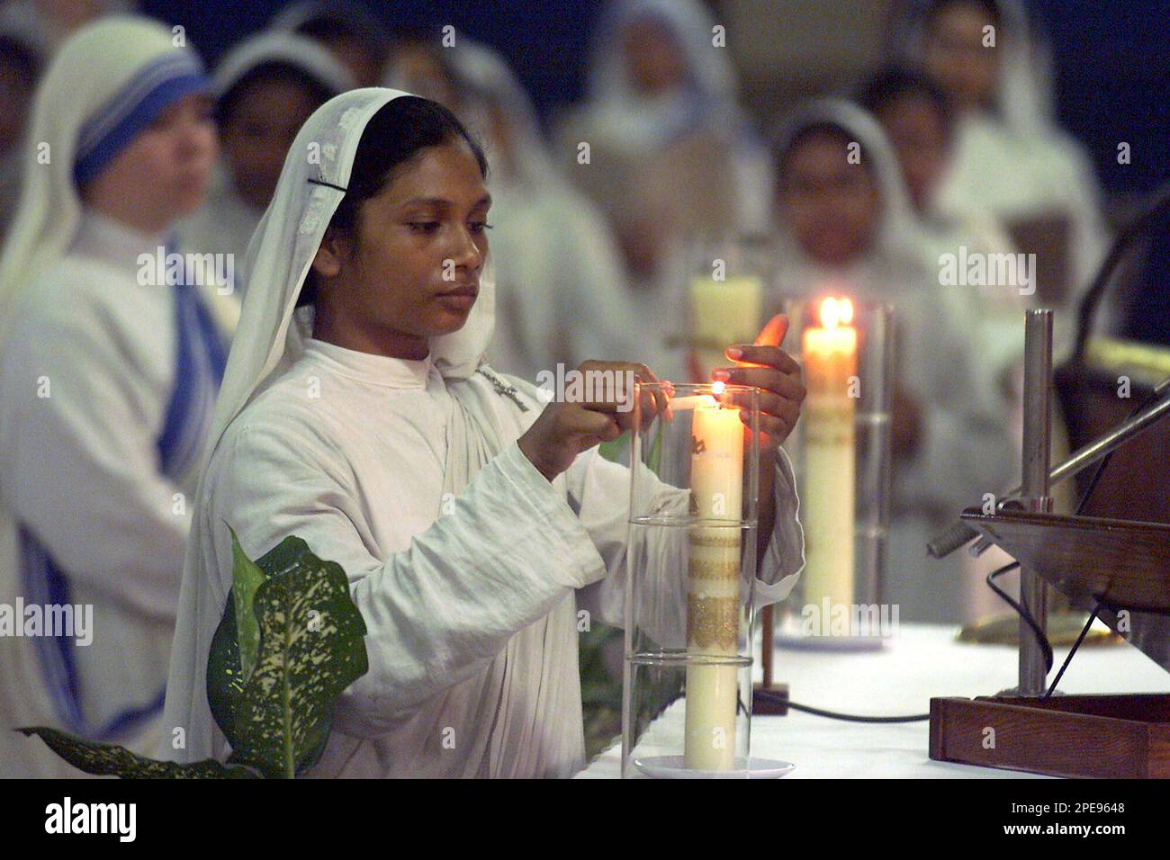 A sister lights a lamp during a holy mass for the life of Pope John ...