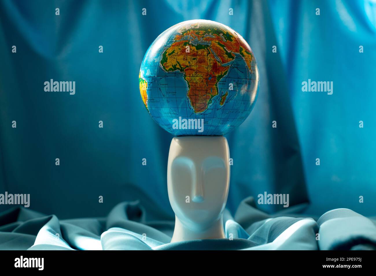 Globe stands on a sculpture of a human head on a blue background Stock ...