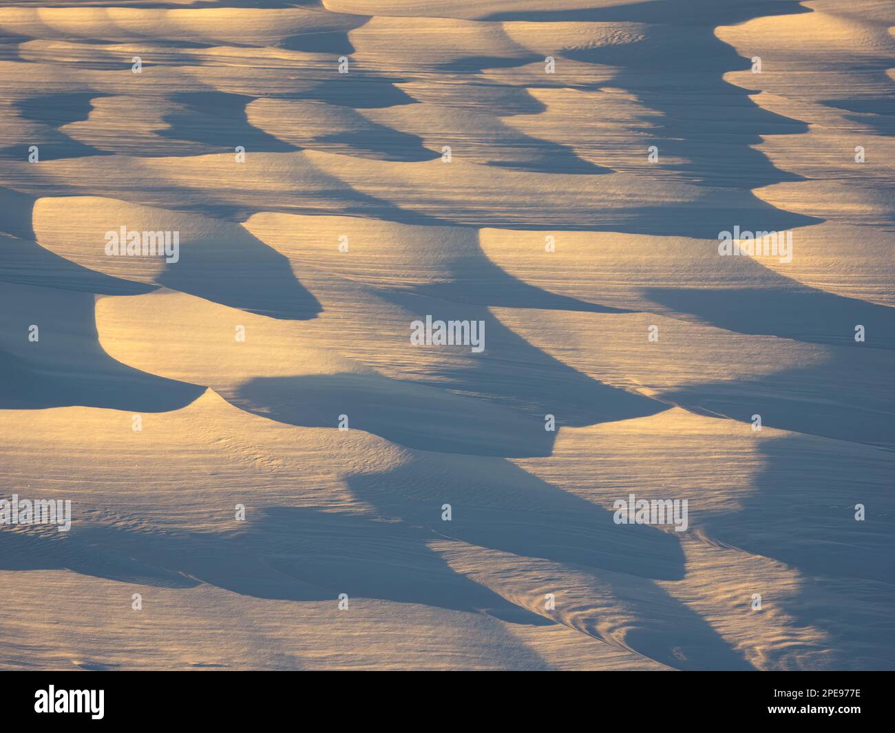 Sunset light highlights scalloped snow patterns on lake in Southcentral ...