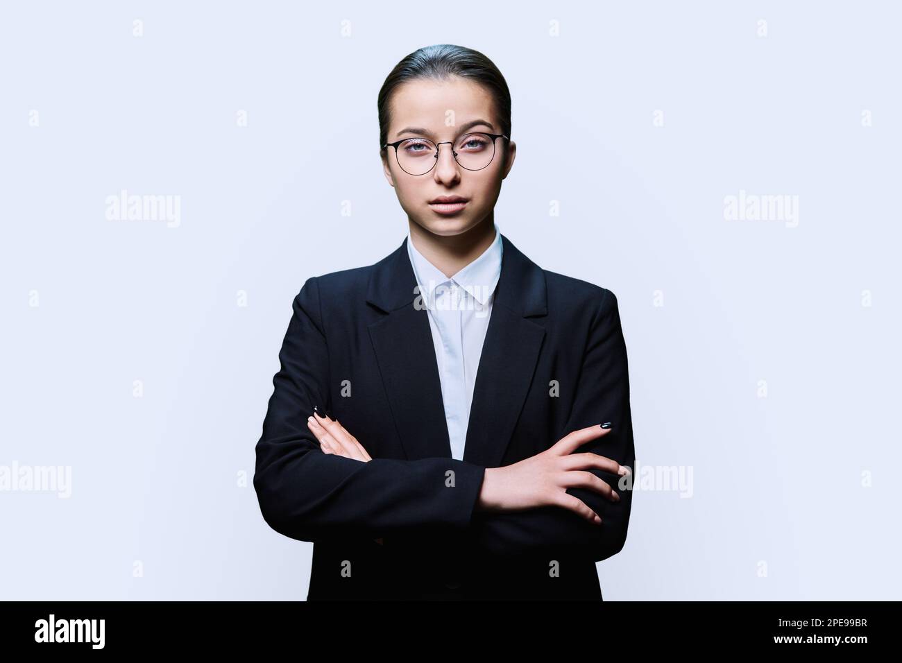 Serious teenage female student in black suit looking at camera on white ...