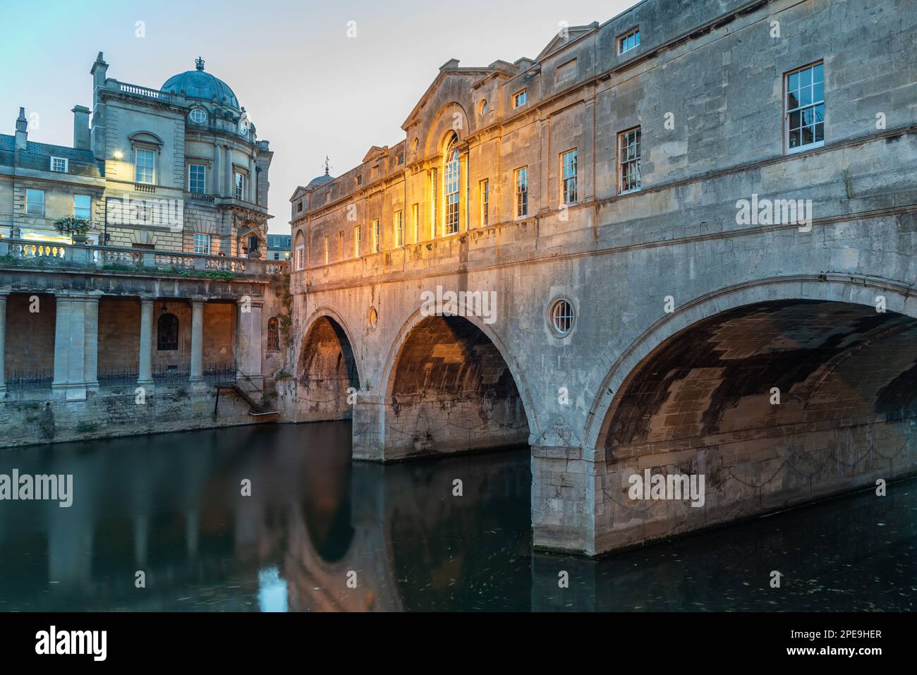 Pulteny Bridge is an arch bridge with shops on its side in Bath city UK ...