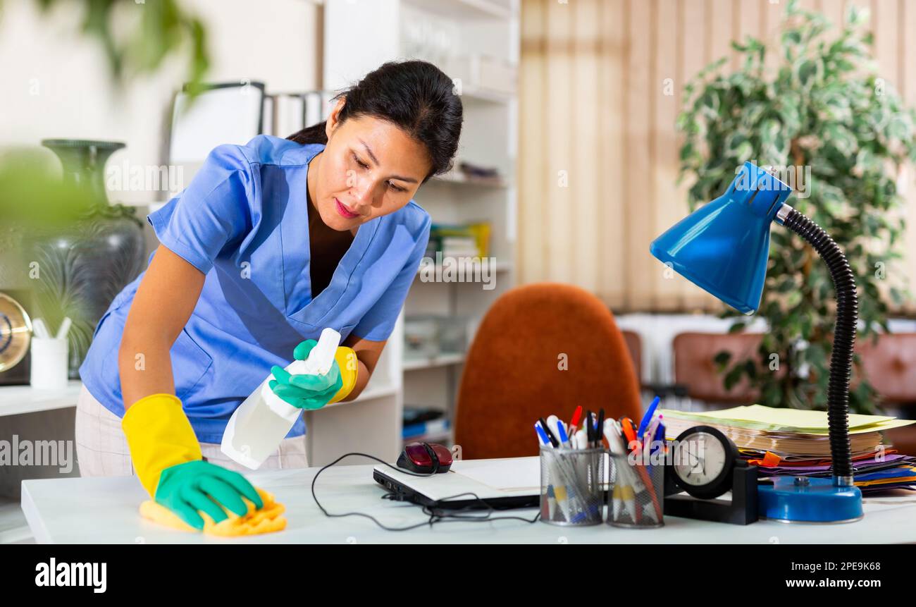 Asian female cleaning desk in office Stock Photo - Alamy