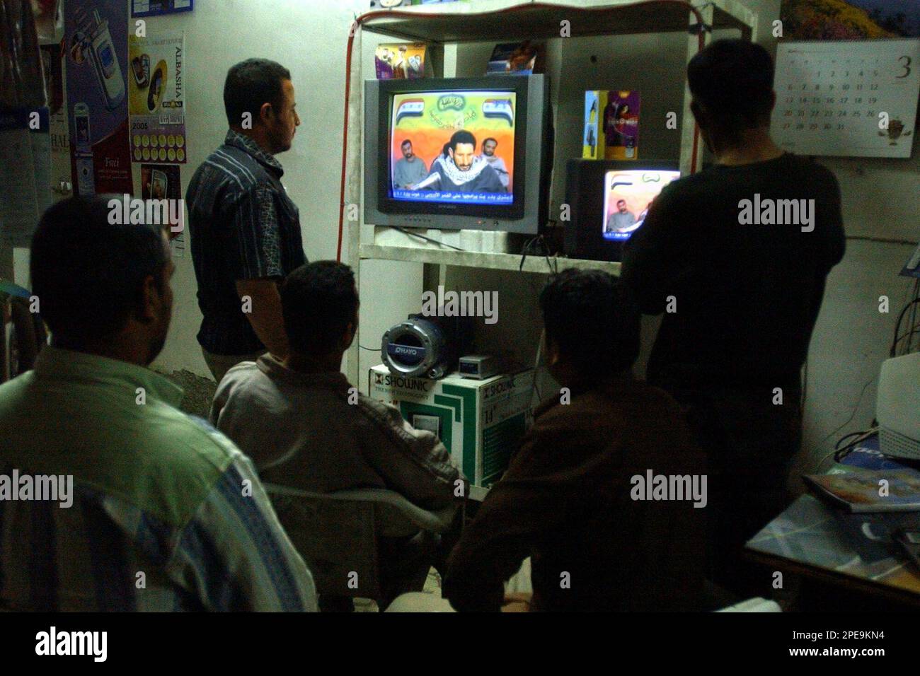 Iraqis gather in a television repair shop in the Sadr City section of ...