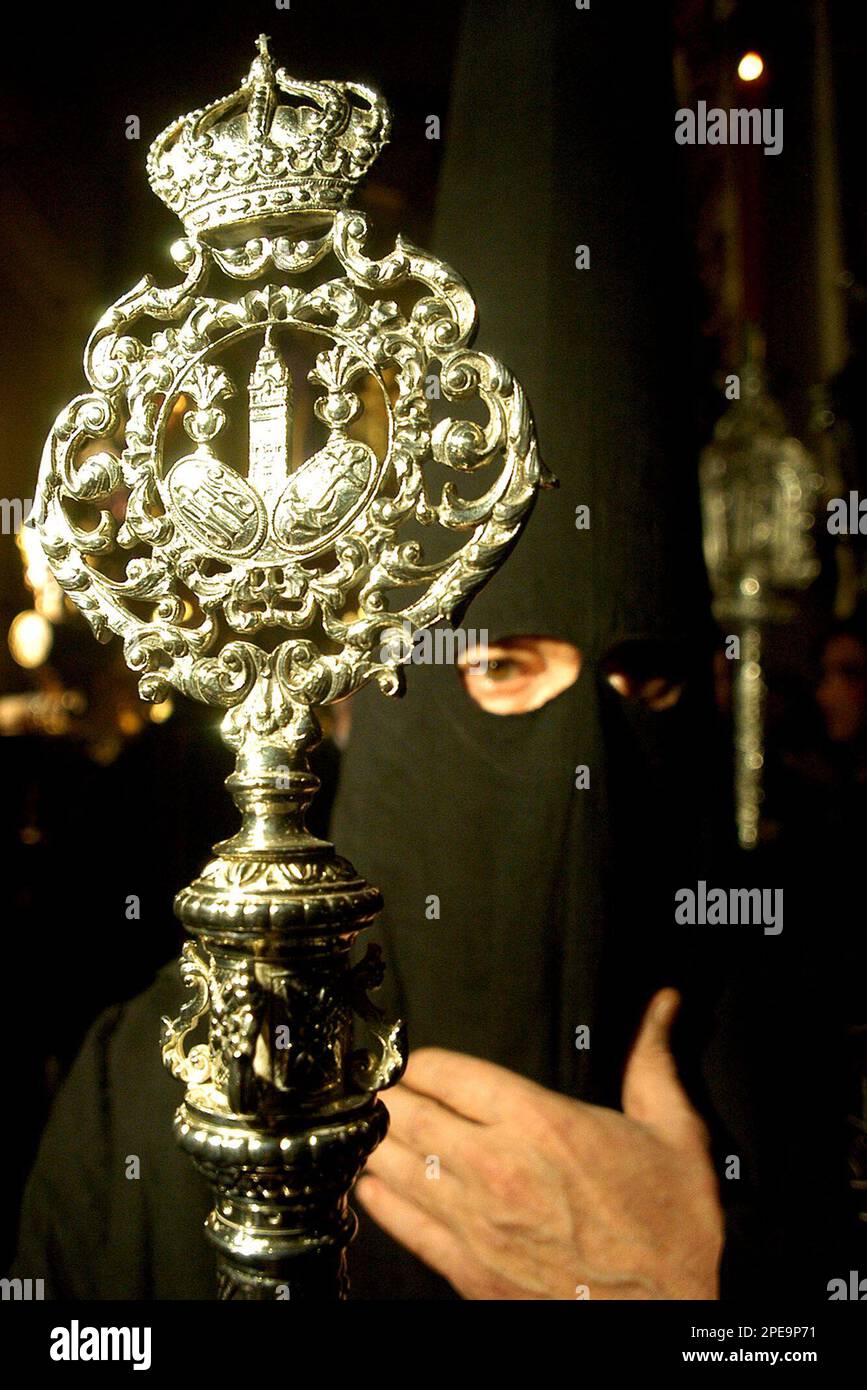 A hooded penitent walks with a decorative staff, during an Easter Holy ...