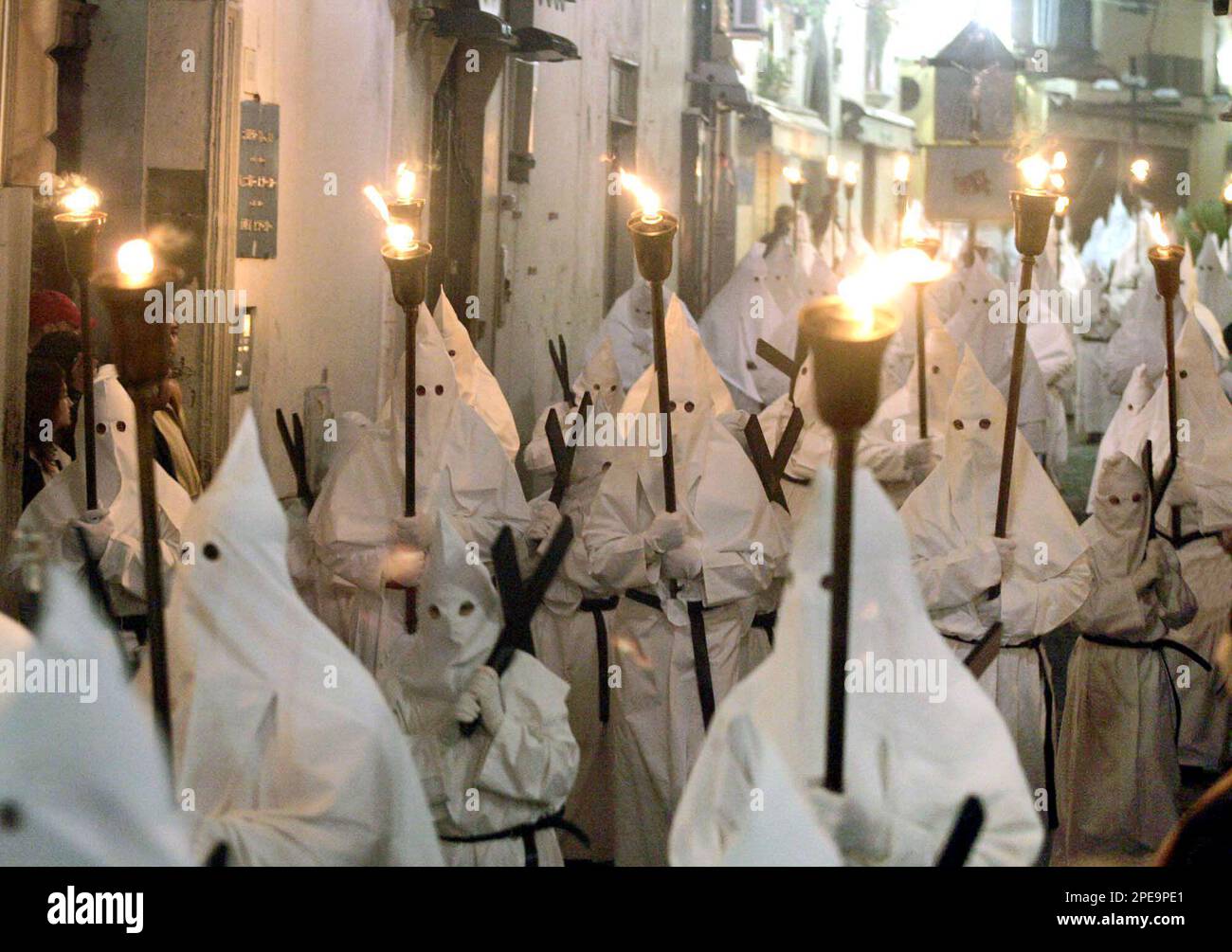 Hooded faithful carry crosses and torches during the Good Friday ...