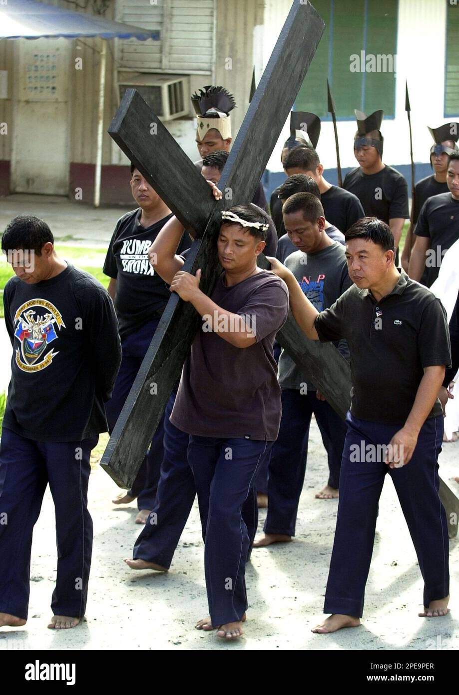 A Filipino policeman carries a cross in repentance for his mistakes ...