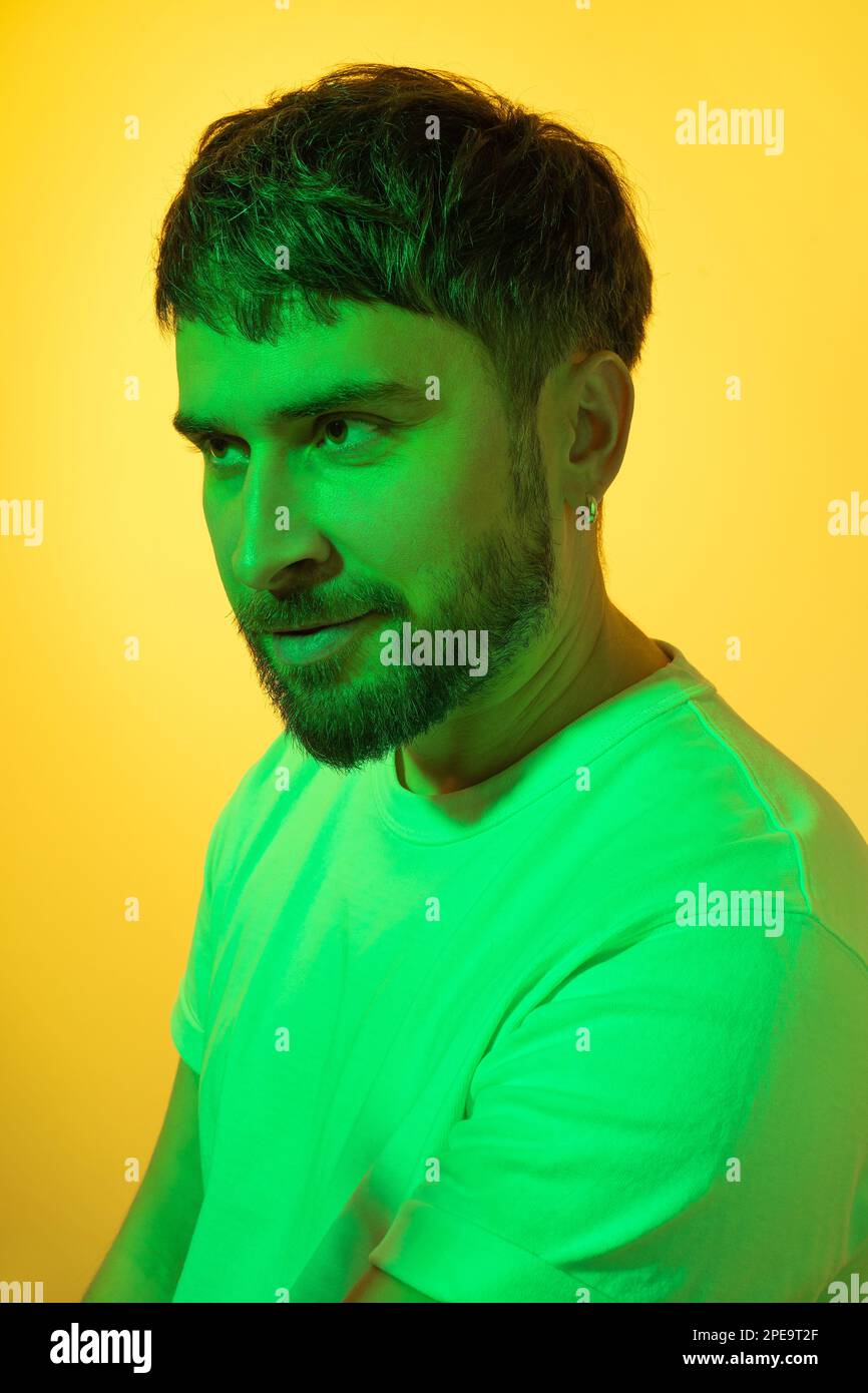 Creative portrait. Smiling man with a sly look in green neon lights on ...