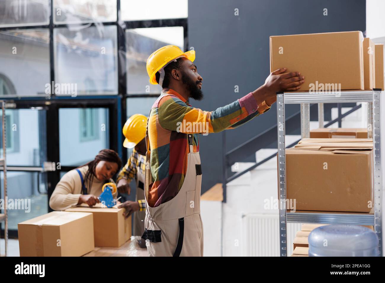 Warehouse package handler choosing cardboard box on shelf while ...