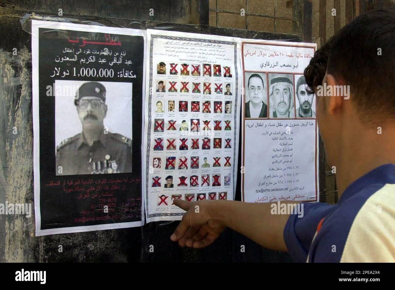 An Iraqi man looks at wanted posters distributed by U.S. forces in ...