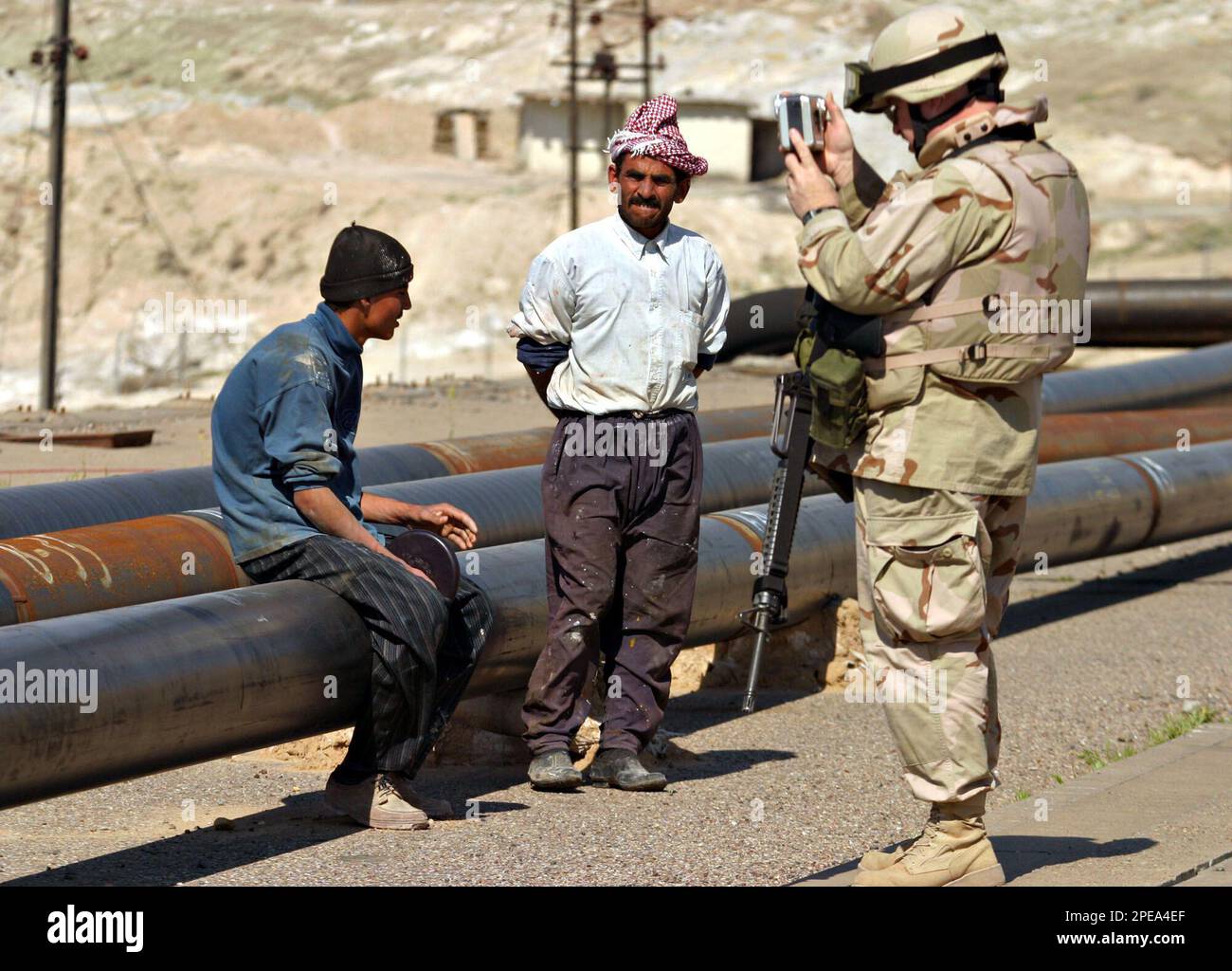 Iraqi workers take a break while a U.S. Army 42nd Infantry Division ...